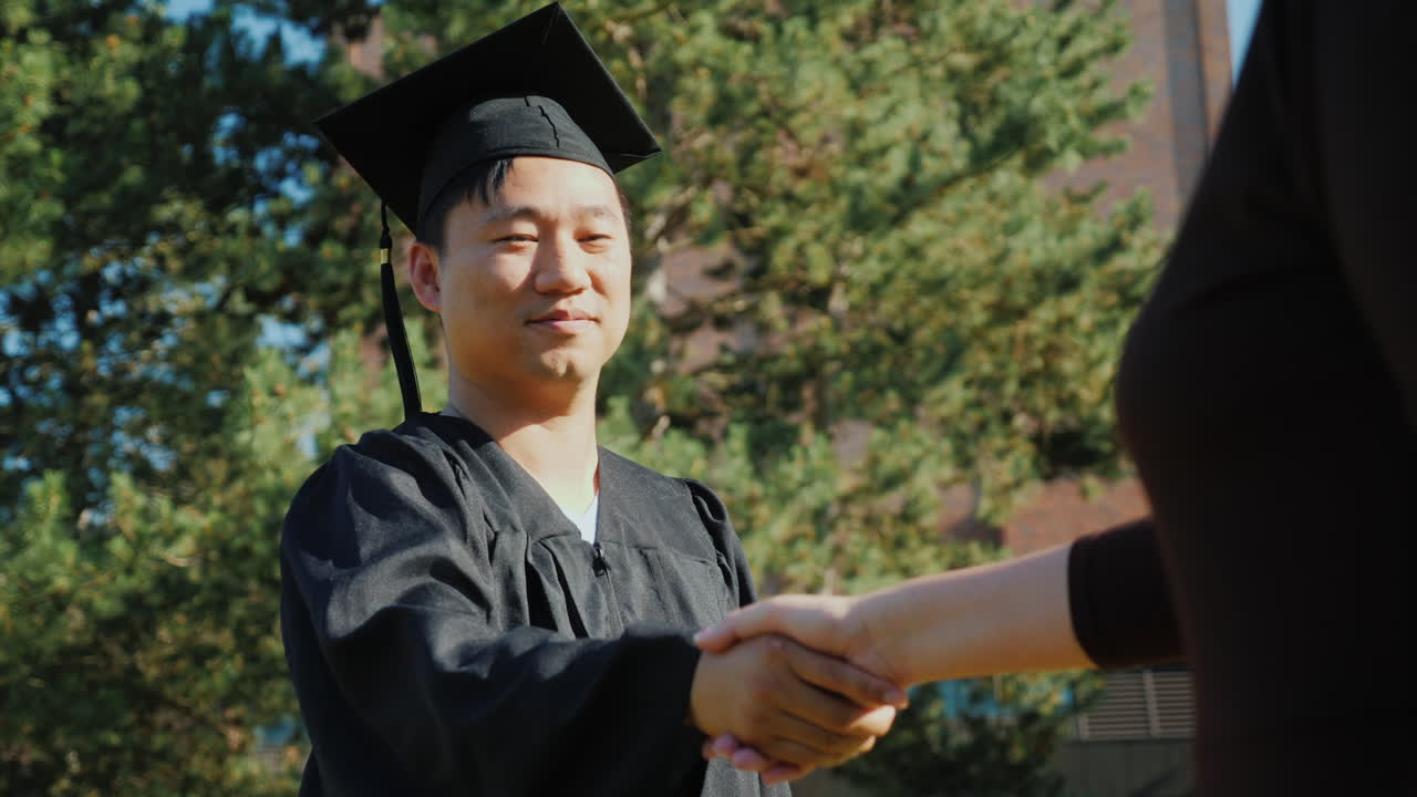 Successful asian man in graduate clothes accepts congratulations they ...