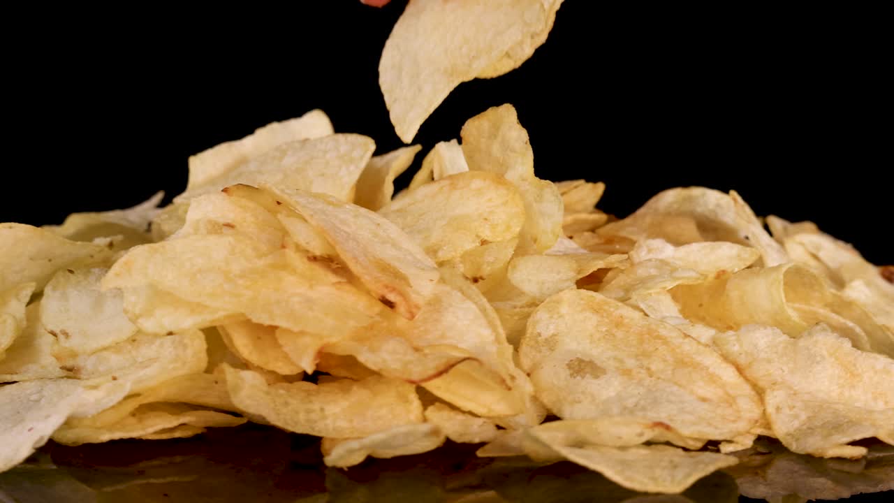 Hand grabs potato chips from pile, rotating and zooming out, under ...