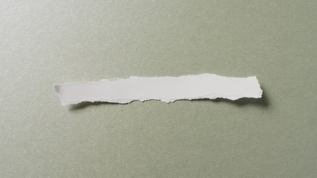 Video de primer plano de un pedazo de papel blanco roto sobre un fondo ...