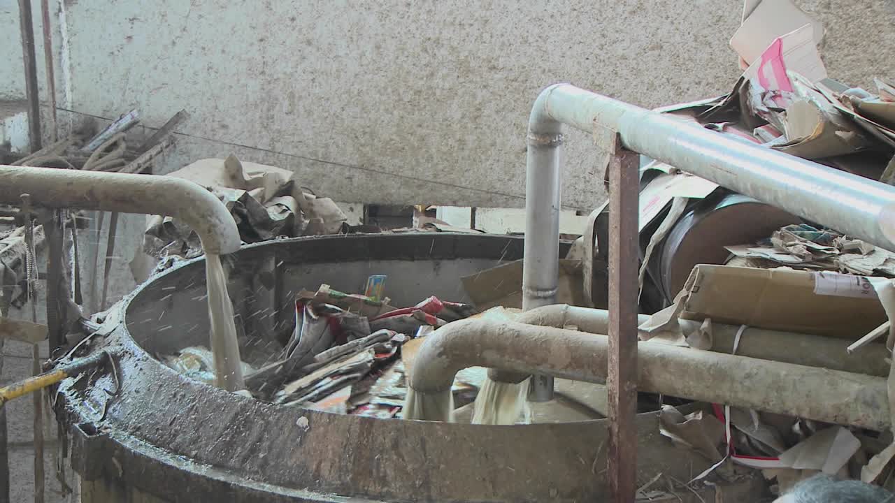 Premium stock video - Cardboard boxes are washed in a crude washing machine