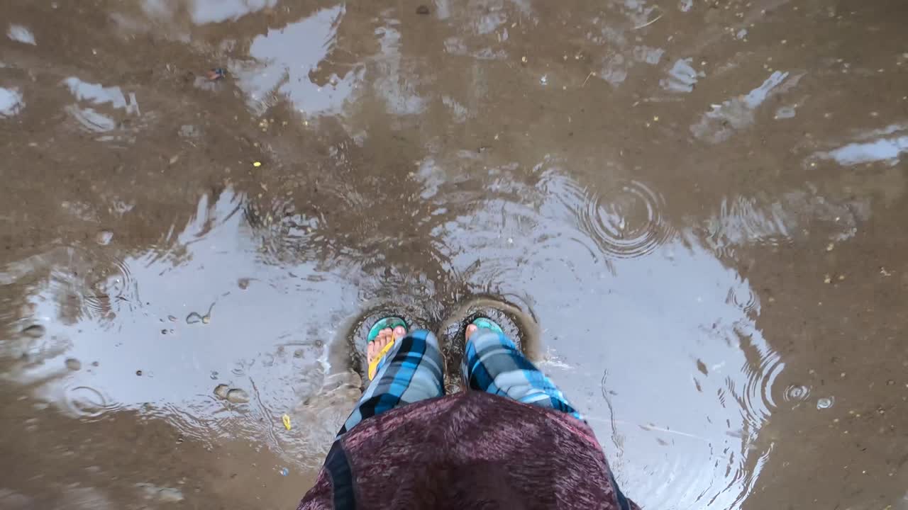 Point of view of a man jumping on a rain paddle on a concrete floor ...