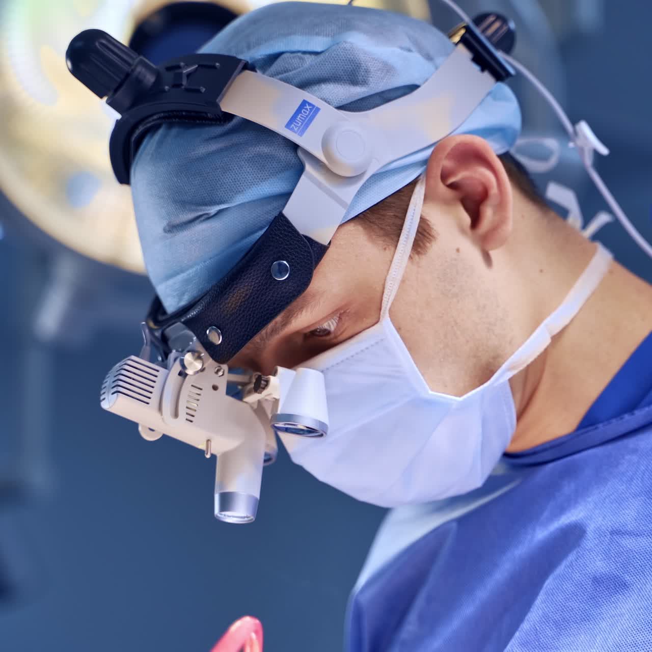 Mid aged male Caucasian neurosurgeon in device glasses at surgery room ...