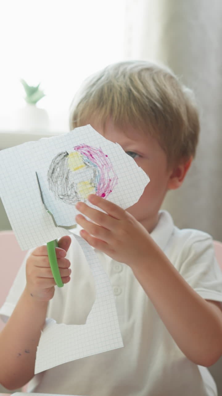 Diligent little boy cuts out circle with drawing of copybook page at ...