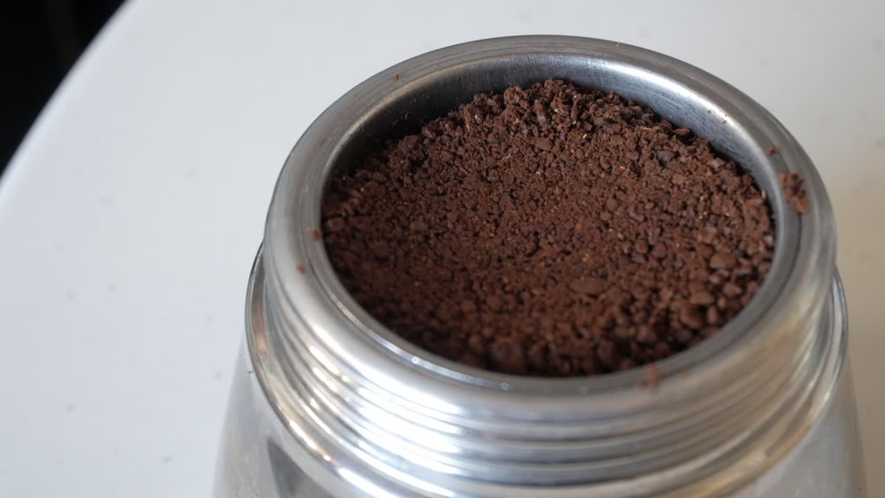 Freshly ground coffee beans in a moka pot, ready for brewing, close-up ...