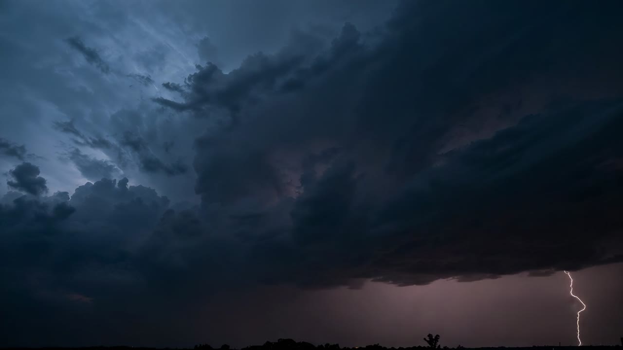 Charging shelf cloud over tree-lined horizon, branching lightning bolt ...