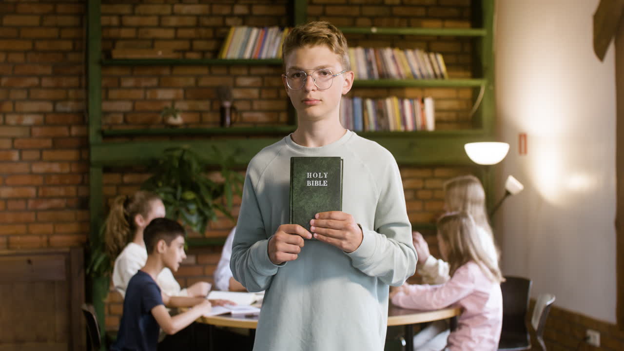 Free stock video - Blond kid holding the holy bible in his hands