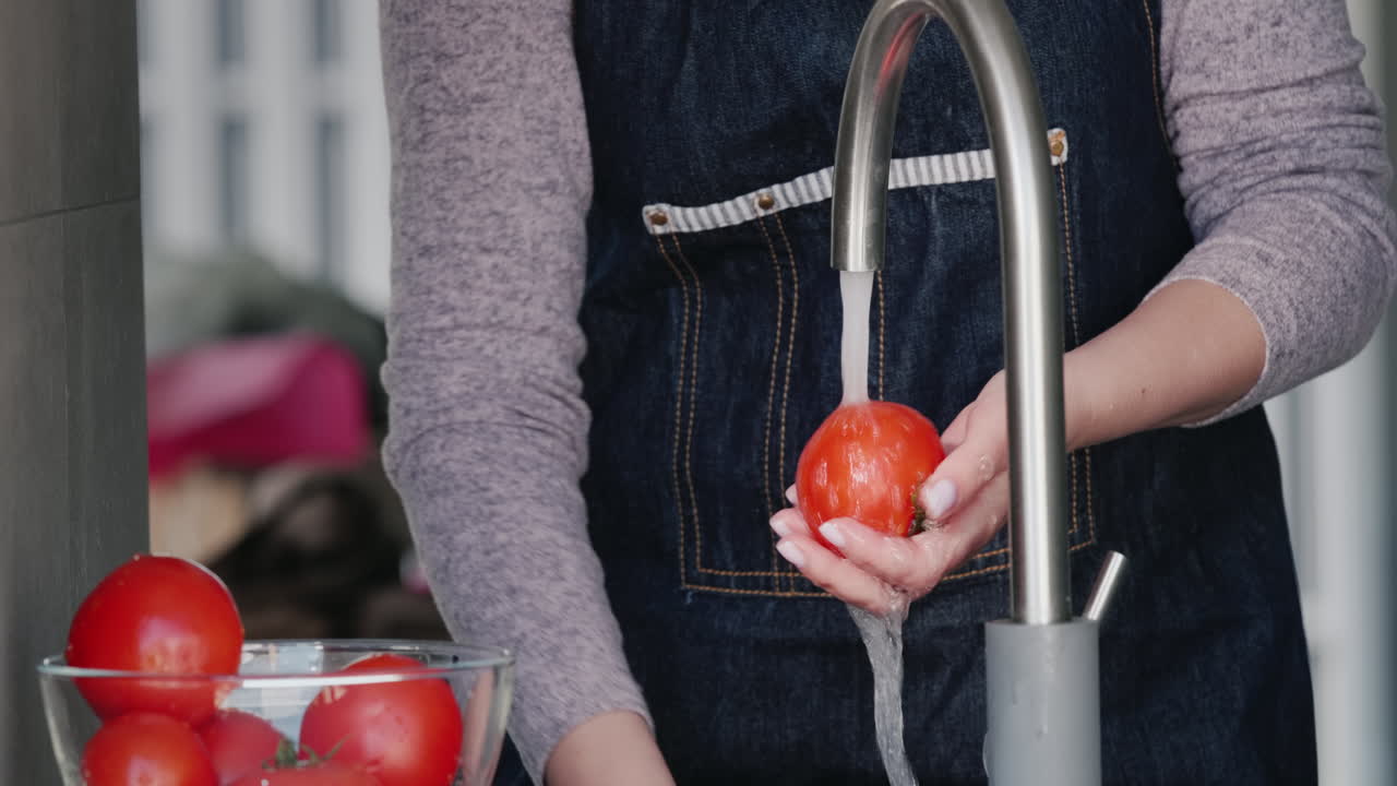 Premium stock video - A woman washes ripe tomatoes under a stream of ...
