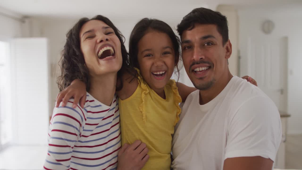 Portrait of happy hispanic parents and daughter standing embracing ...