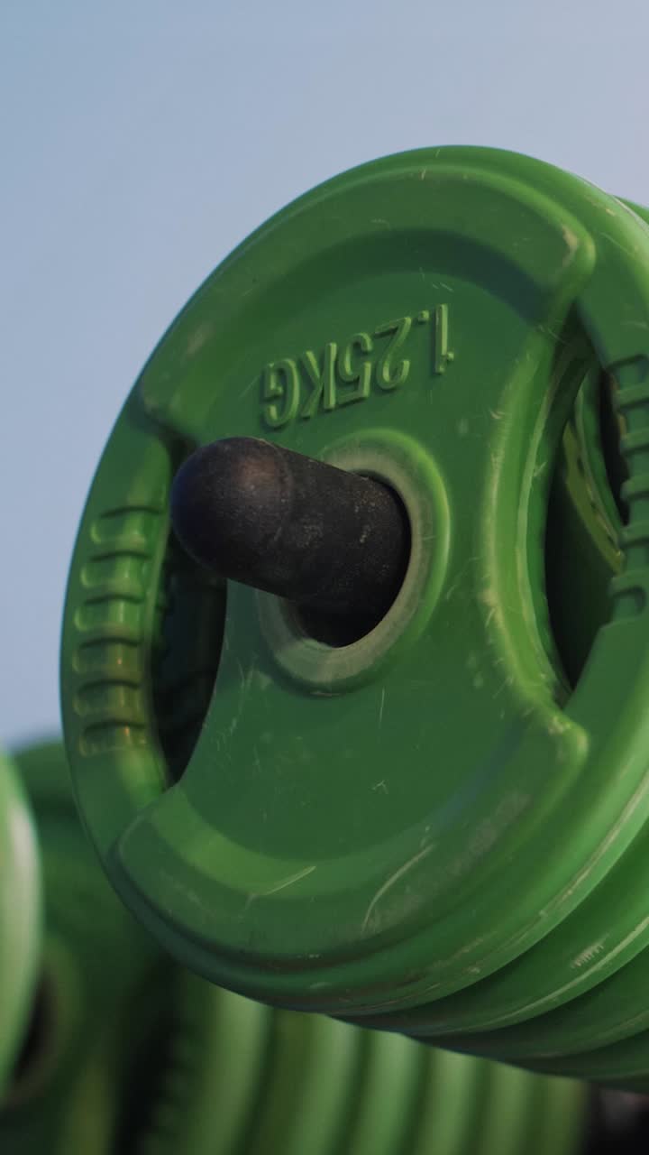 Close-up of green 1.25 kg barbell plates neatly stacked on rack, ready ...