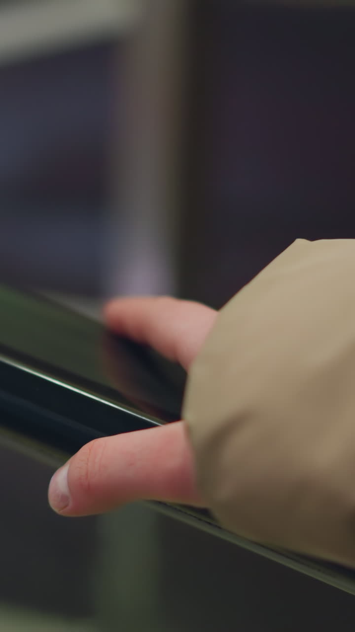Close-up of a hand gripping a moving rail, with a blurred background ...