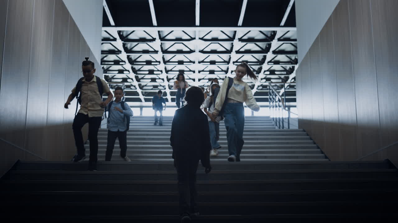 Depressed little boy going upstairs near lively pupils crowd. Children ...