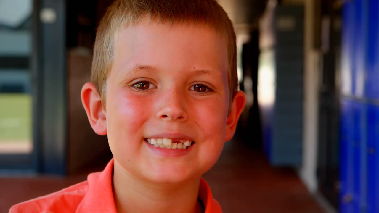 Premium stock video - Portrait of cute schoolboy standing in corridor 4k