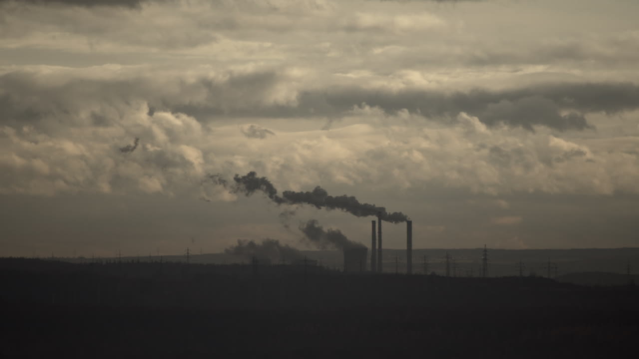 Premium stock video - Smoke billows from factory in distance on gray ...