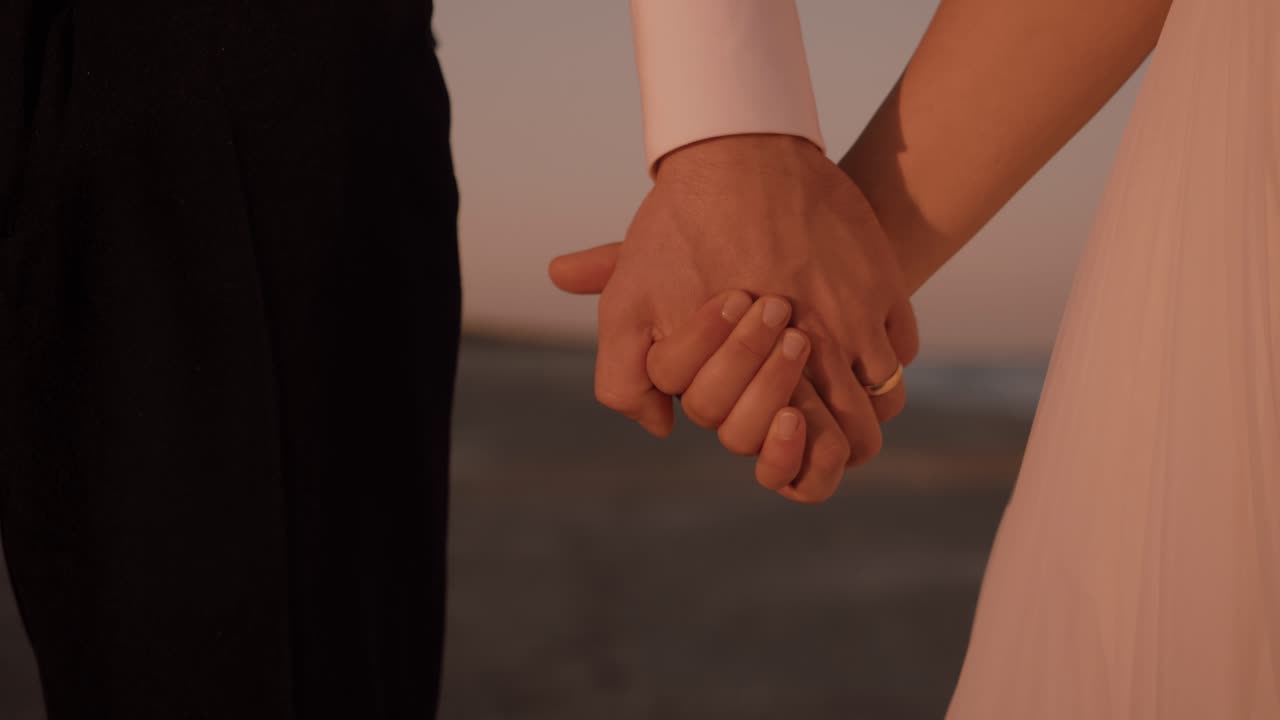 Couple taking hands in the light of the sun by the seaside, close up ...