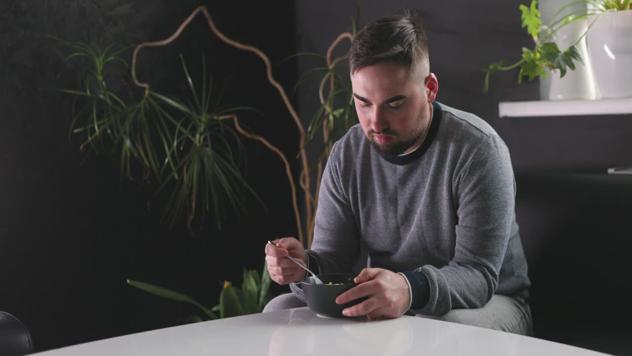Hungry man sitting on sofa and eating tasty noodles Free Stock Video ...