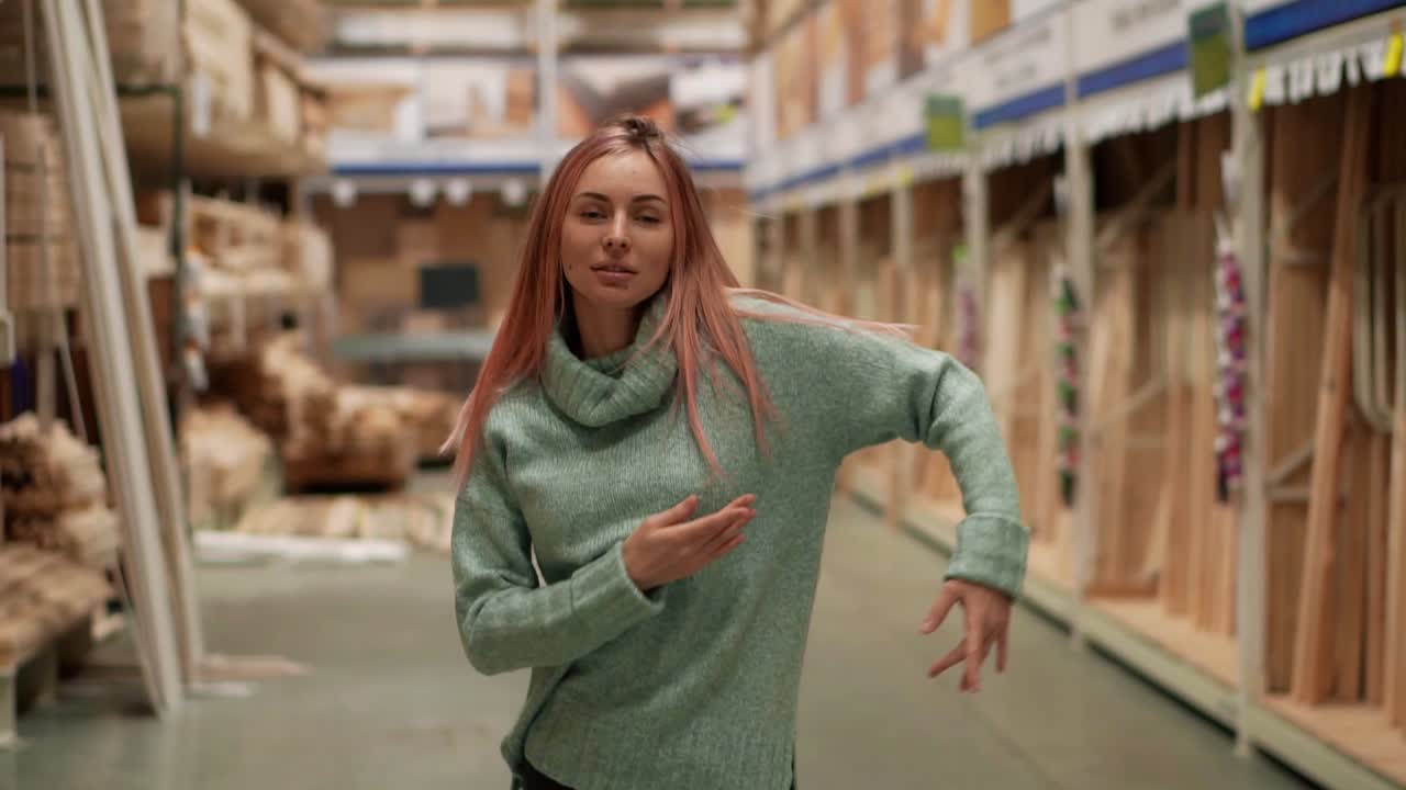 Premium stock video - Young girl dances in hardware store relaxfully