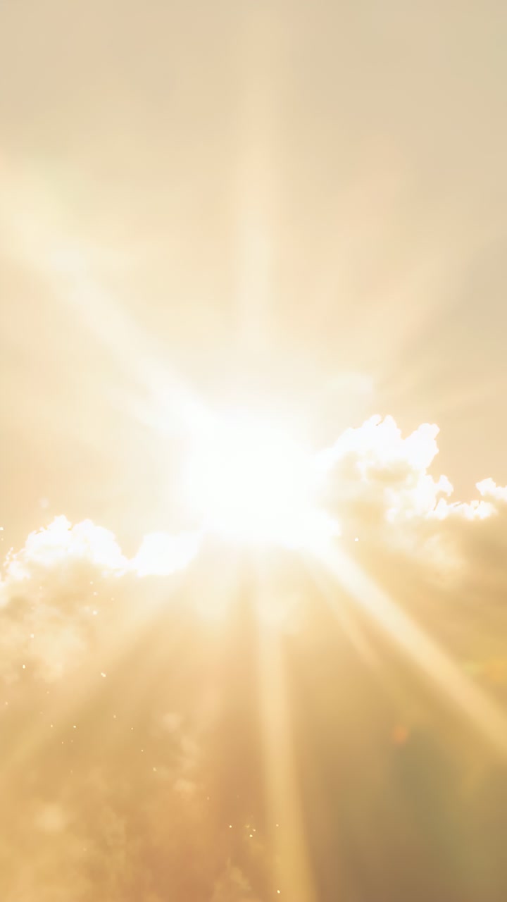 Vertical video: Peeking sun sending sun rays through sky above thin ...