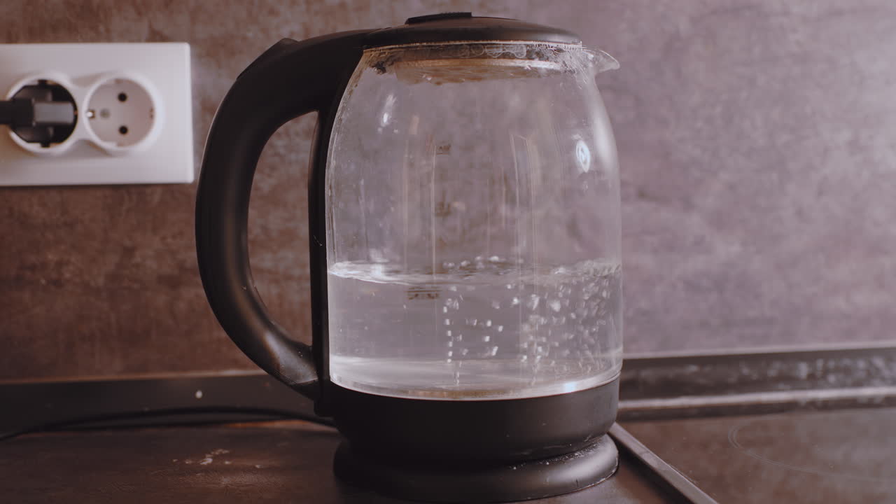 Close up of transparent electric kettle with water heating and bubbling ...