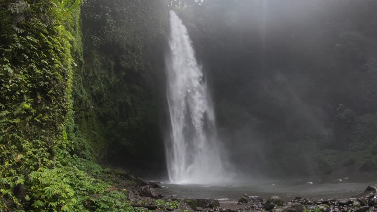 A Big Waterfall Crashing Down On Big, Black Rocks In The Jungle Of Bali ...