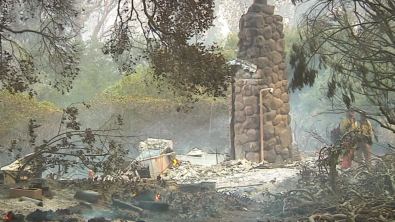 Fire Crews Mop Up Around A Burned And Charred Home Following The ...