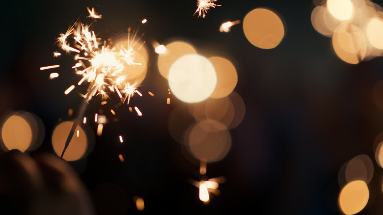 People holding light up sparklers at night, celebrating. Round ...