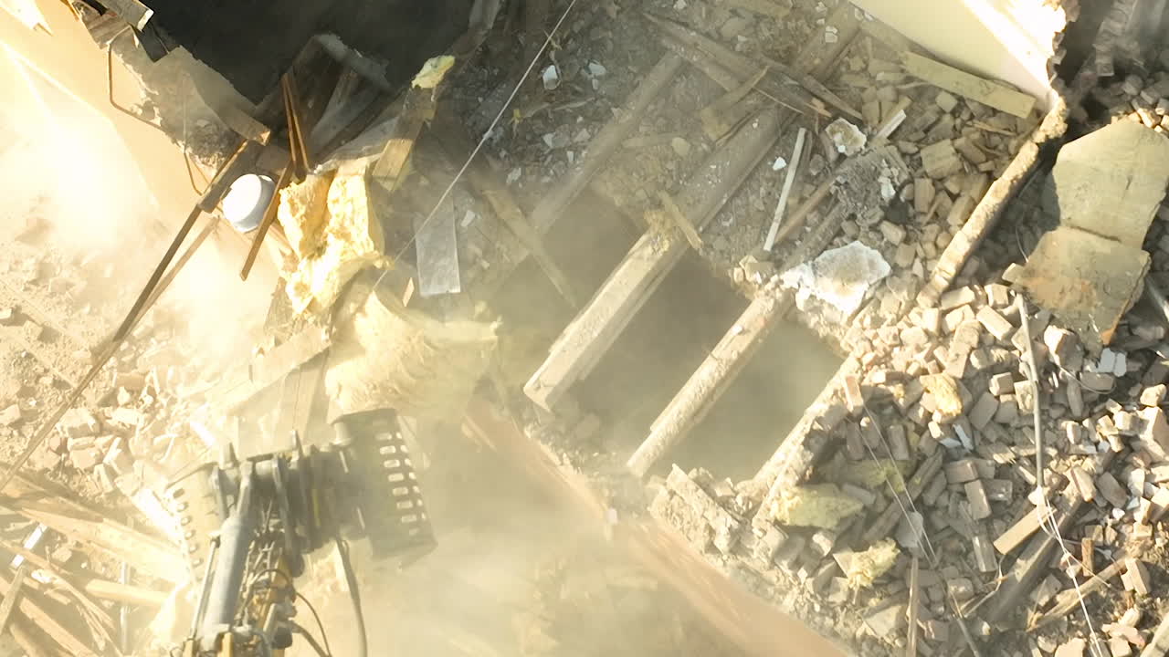 Close-up aerial view of an excavator claw clearing rubble and ...