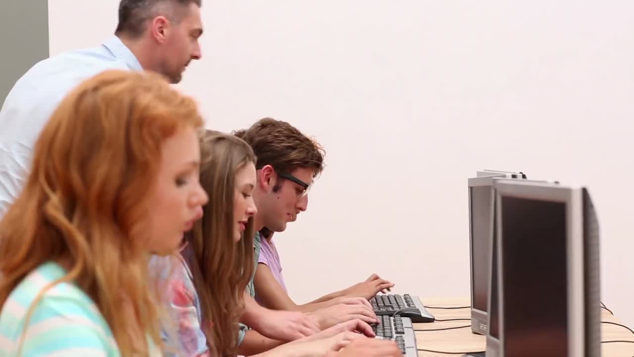 Premium stock video - Students working in computer room with lecturer