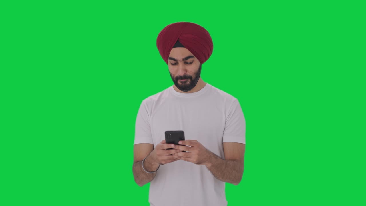 Premium stock video - Happy sikh indian man texting someone green screen