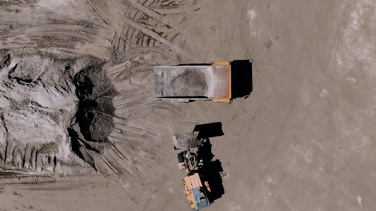 Aerial overhead shot of an excavator loading sand into a haul truck ...
