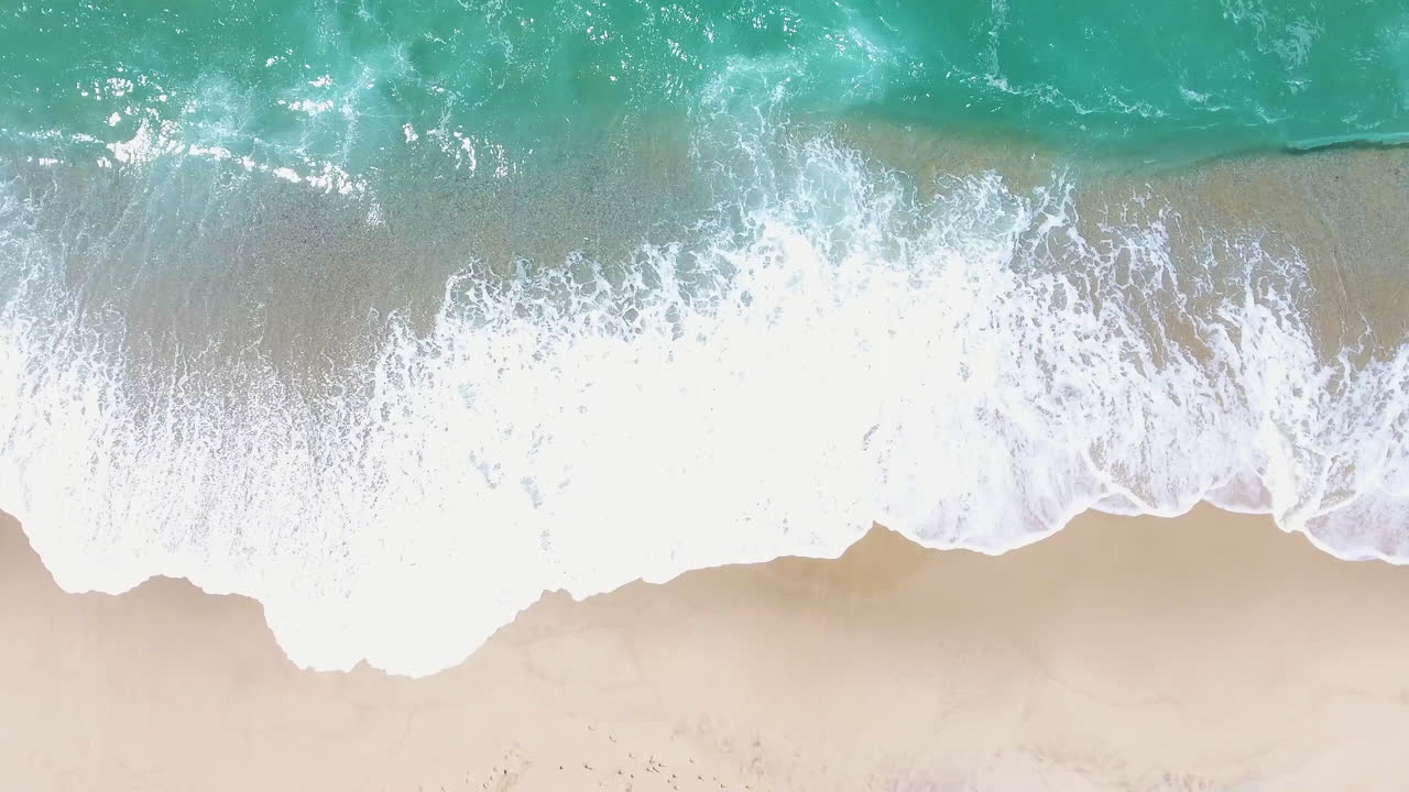Premium stock video - Aerial waves breaking slowly the sand