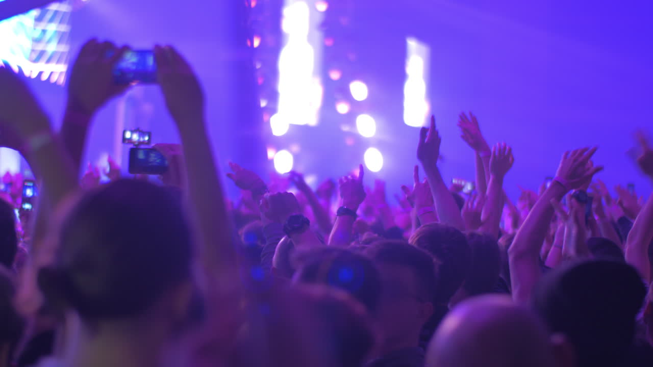 Premium stock video - Happy fans dancing with hands up at rock concert