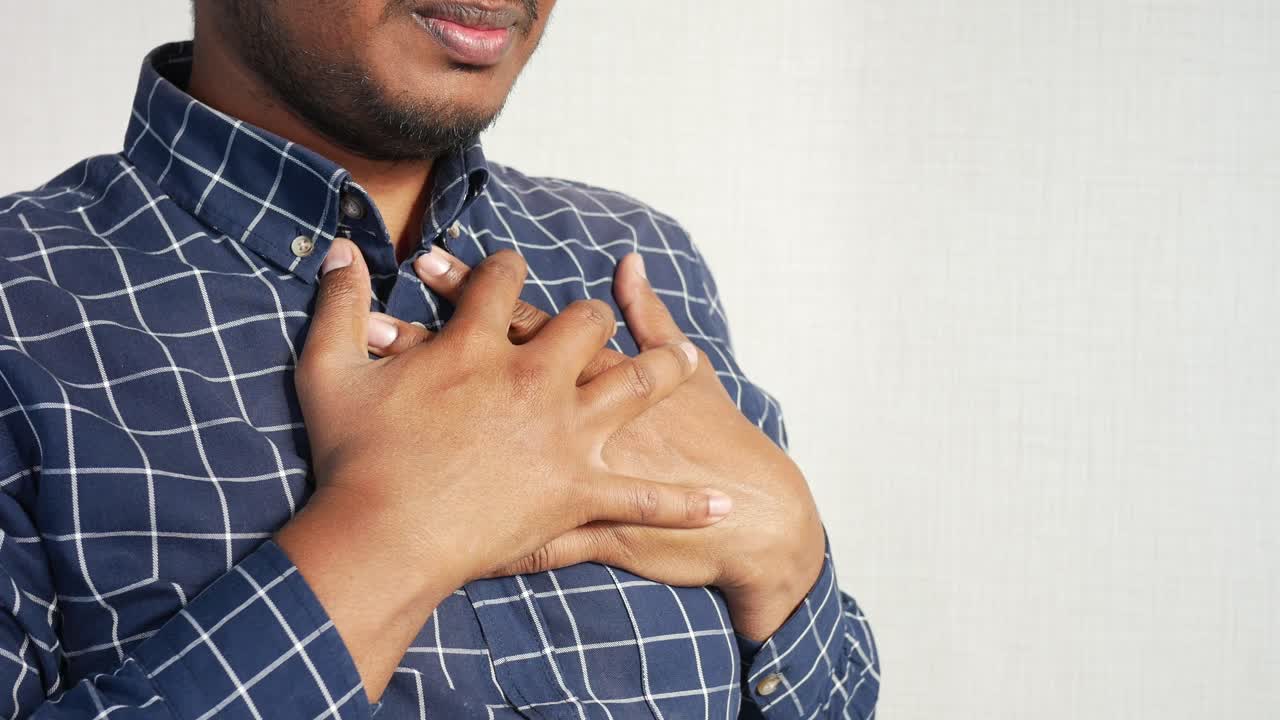 Premium stock video - A man holding his chest with both hands