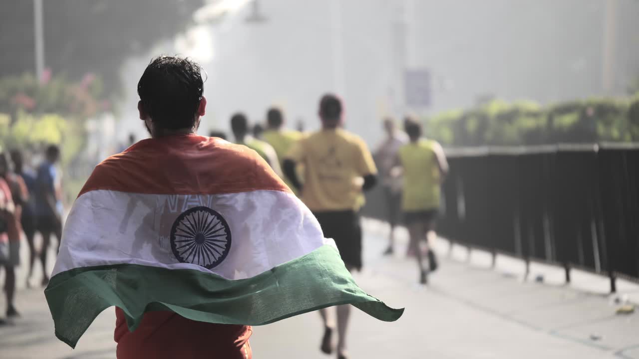 Back shot of a young runner carrying an indian national flag or ...