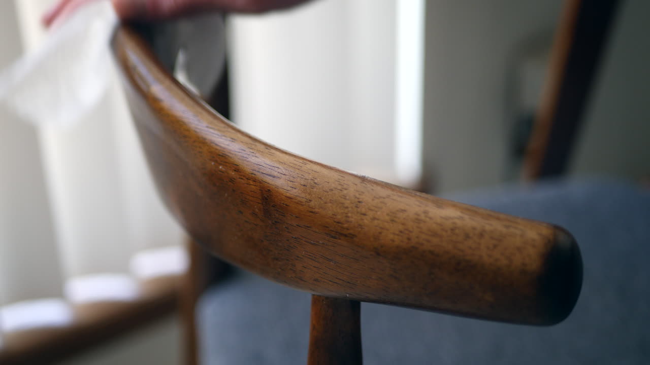 A hand cleaning dust and germs off of wood chair furniture with an ...