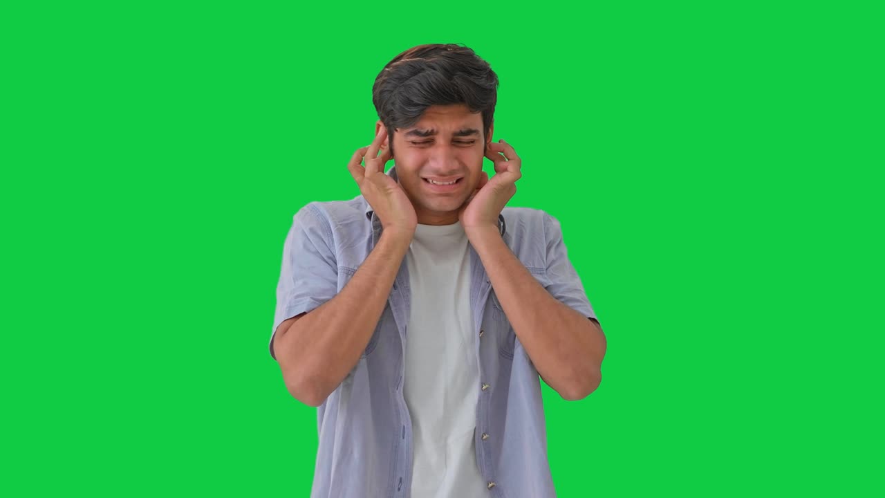 Premium stock video - Indian boy disturbed by loud noises green screen