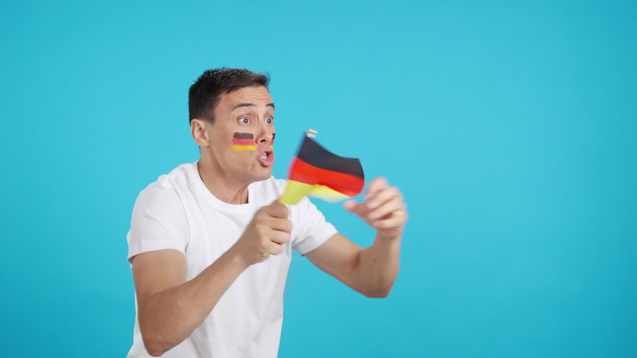 German supporter screaming and waving a national flag looking away ...