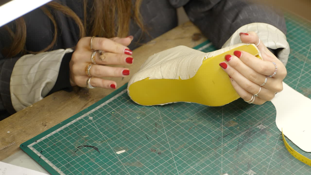 Female craftsperson working on shoe last making template in small ...