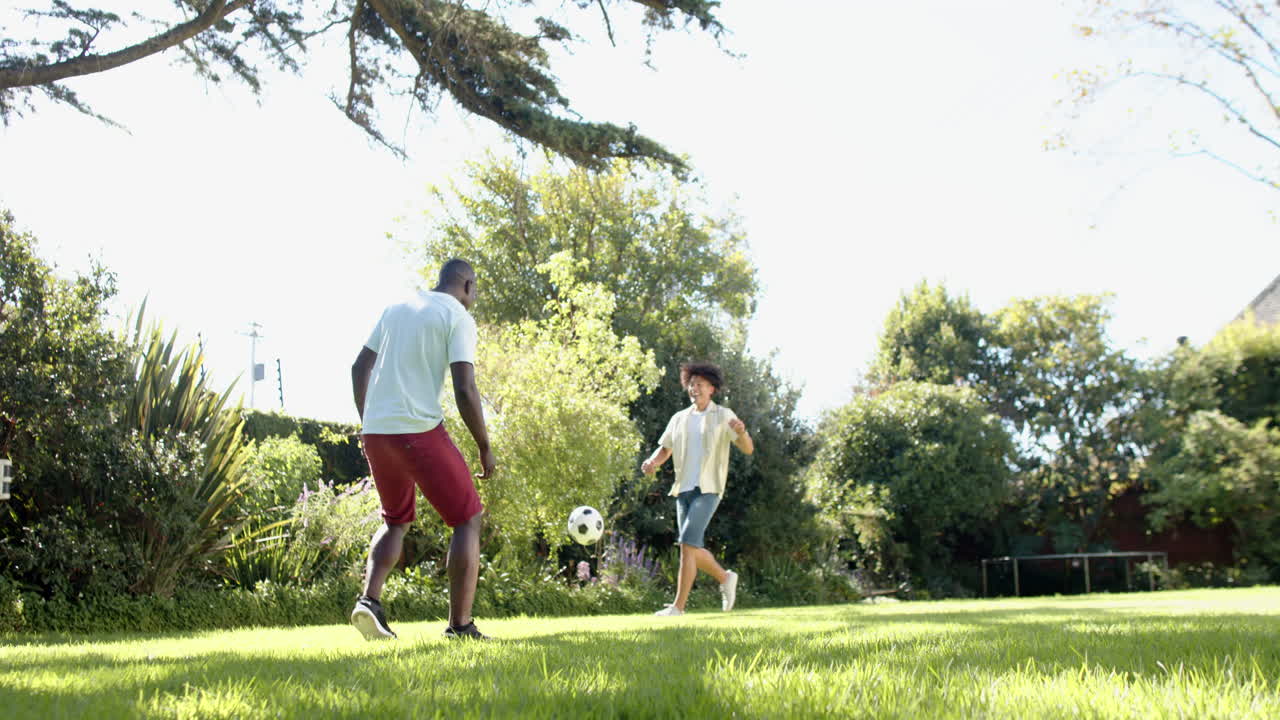 Playing soccer in backyard, two multiracial male friends enjoying ...