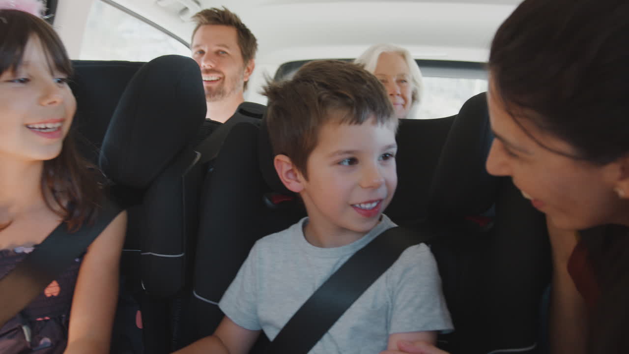 Multi Generation Family Sitting In Back Of People Carrier Being Driven ...