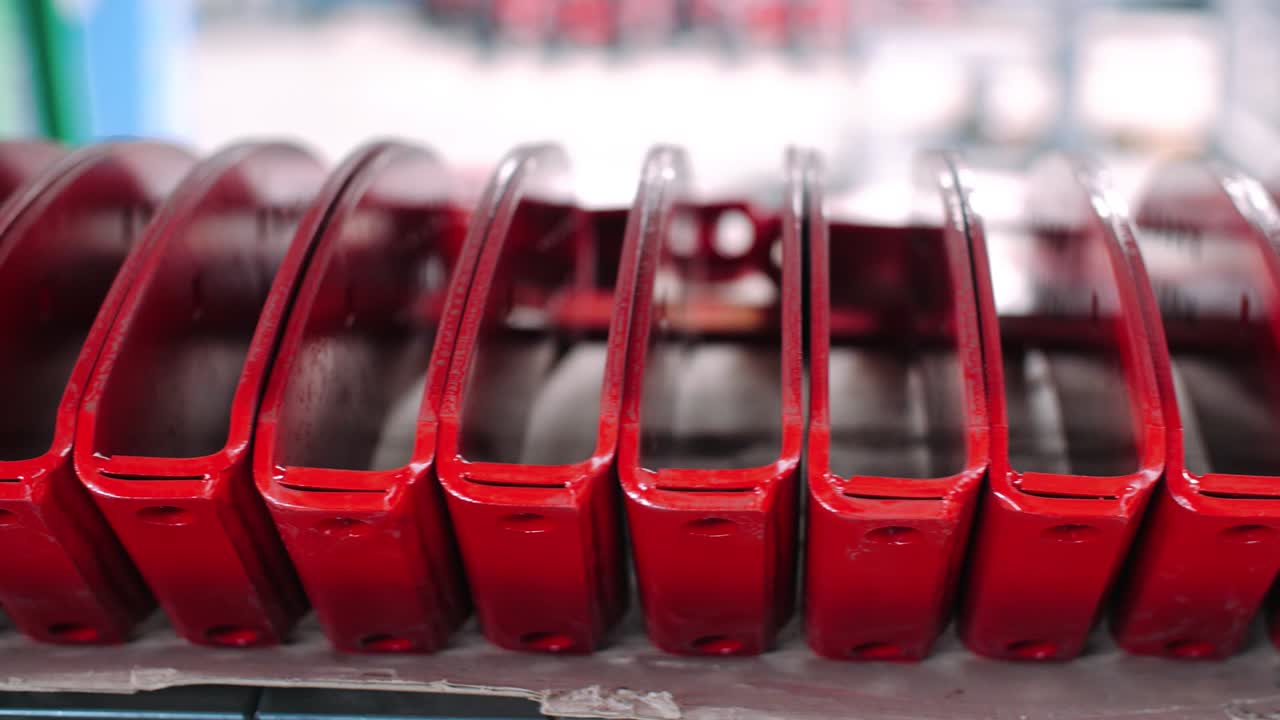 Row of metal details in red color after painting. Painted billets on ...