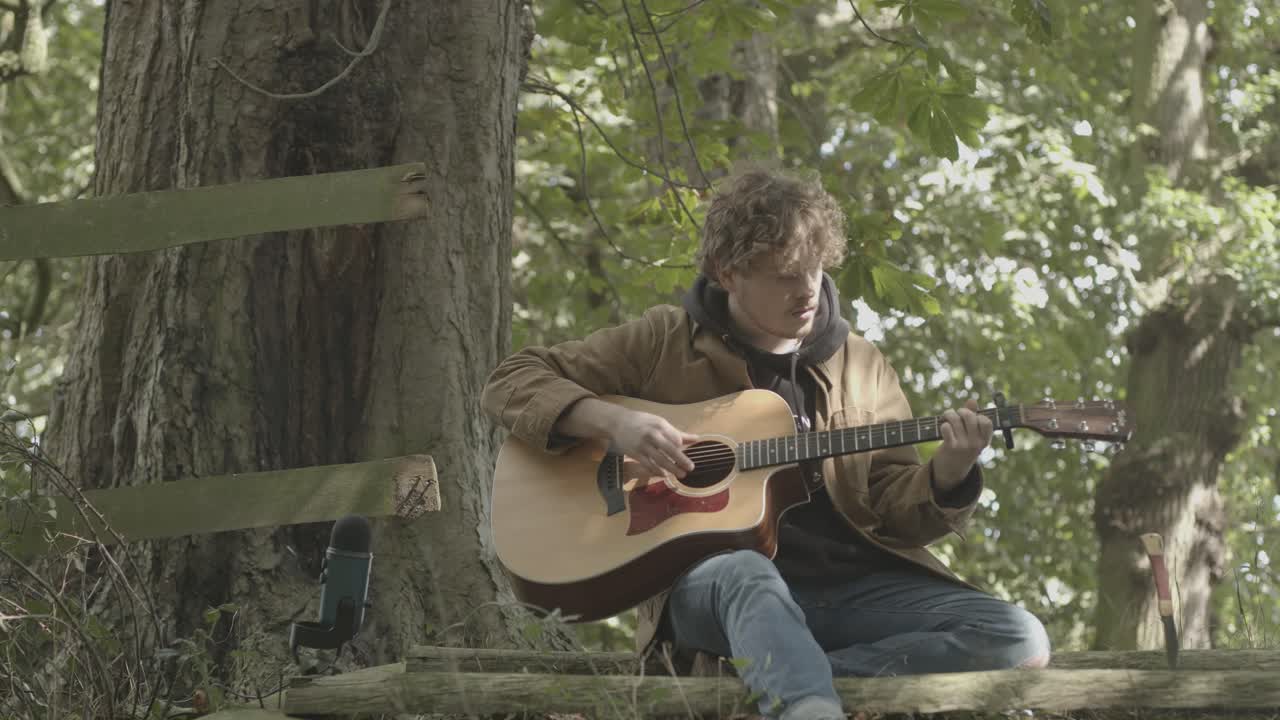 Premium stock video - Young man plays acoustic guitar and sings sitting ...