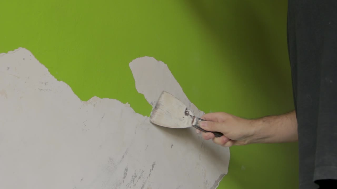 Steady Wide Shot Of A Man Scraping Off Green Paint From A Wall Free ...