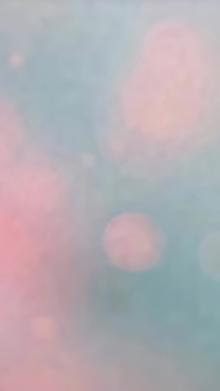 Vertical video: Displaying blurred orbs shifting, shimmering in pastel ...