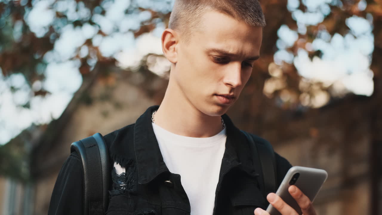 Young student using mobile phone outdoors. | Free Stock Video Footage