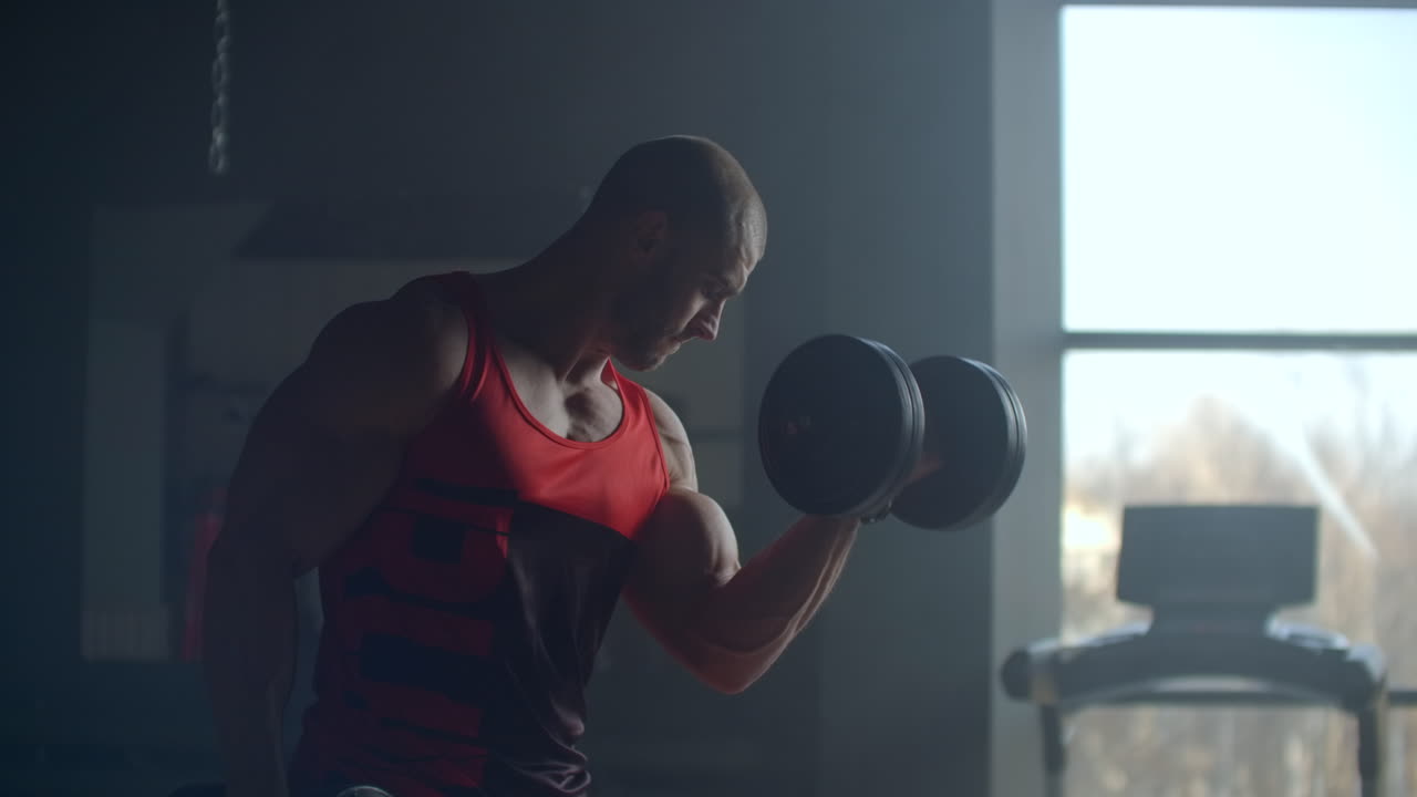 Premium stock video - An athlete lifts weights to train your biceps in ...
