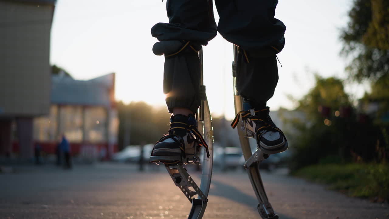 Man walking on spring stilts wearing dark pants and sneakers during ...