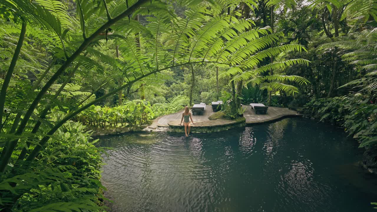 Premium stock video - Woman sitting on tropical pool edge in jungle ...