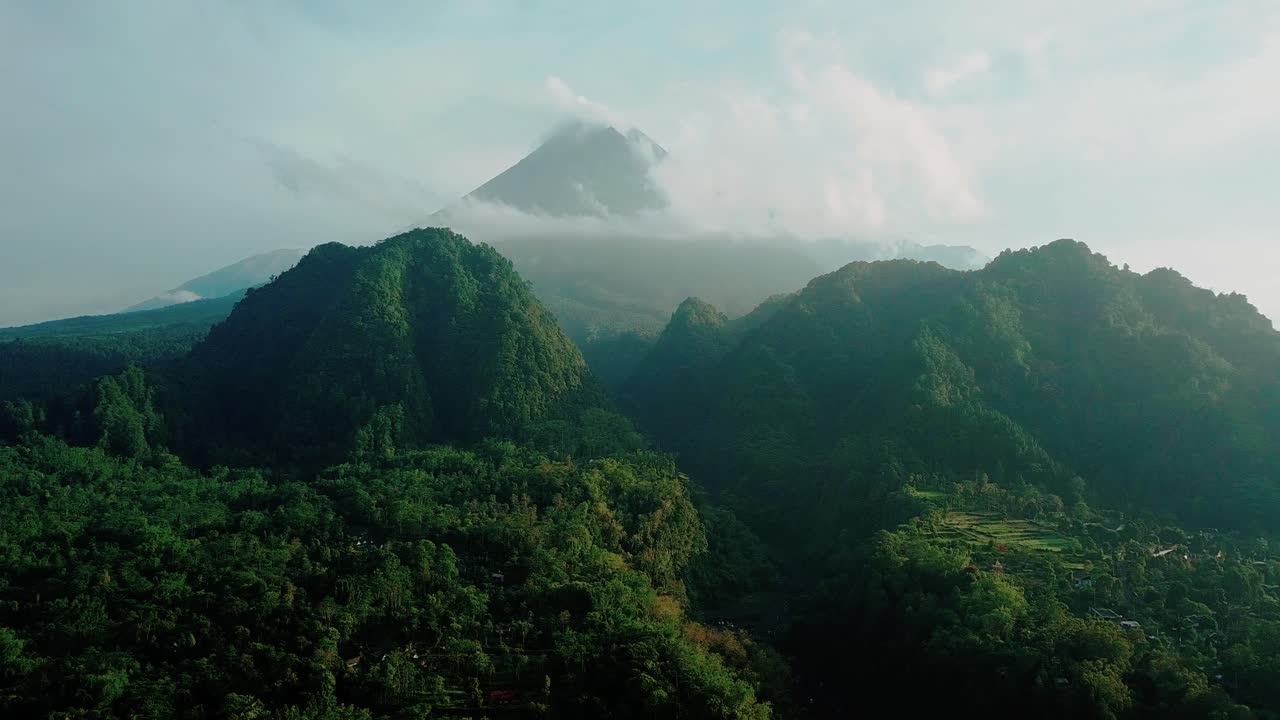 Drone shot of merapi volcano with two hills and overgrown with dense ...