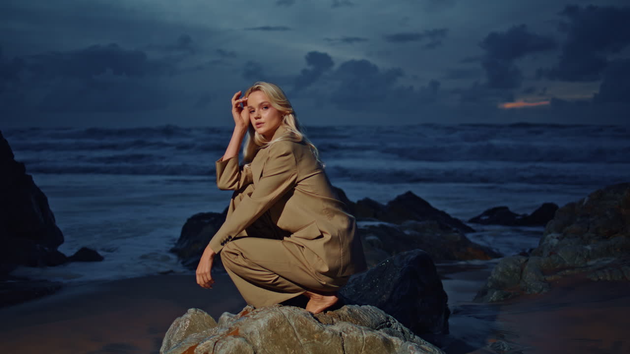 Woman modeling coast rocks at twilight sky. Fashion girl shooting ...