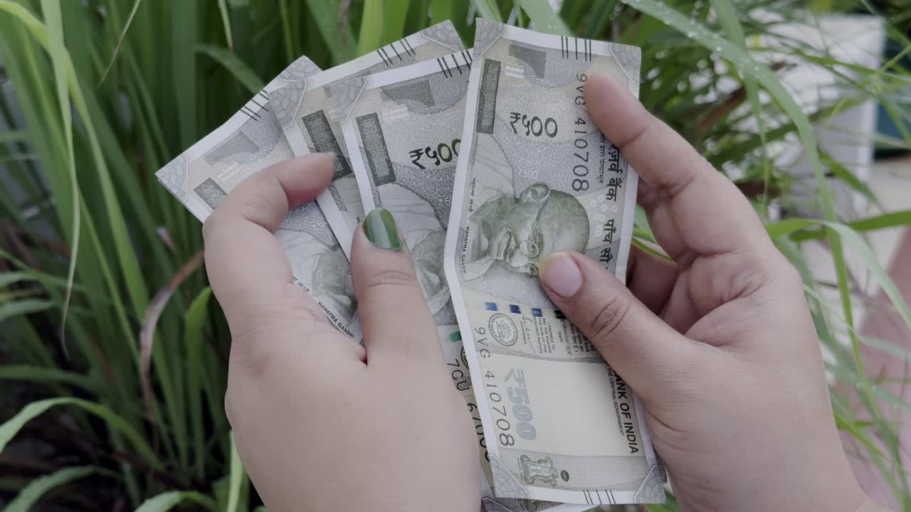 Closeup of a women's hand counting an 500 rupee note of indian currency ...